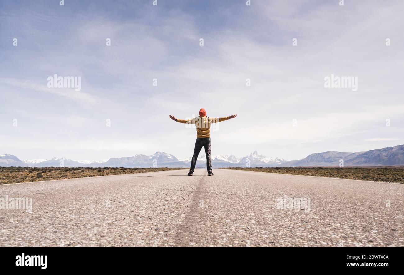 Man outstretched arms standing on road remote landscape patagonia hi ...