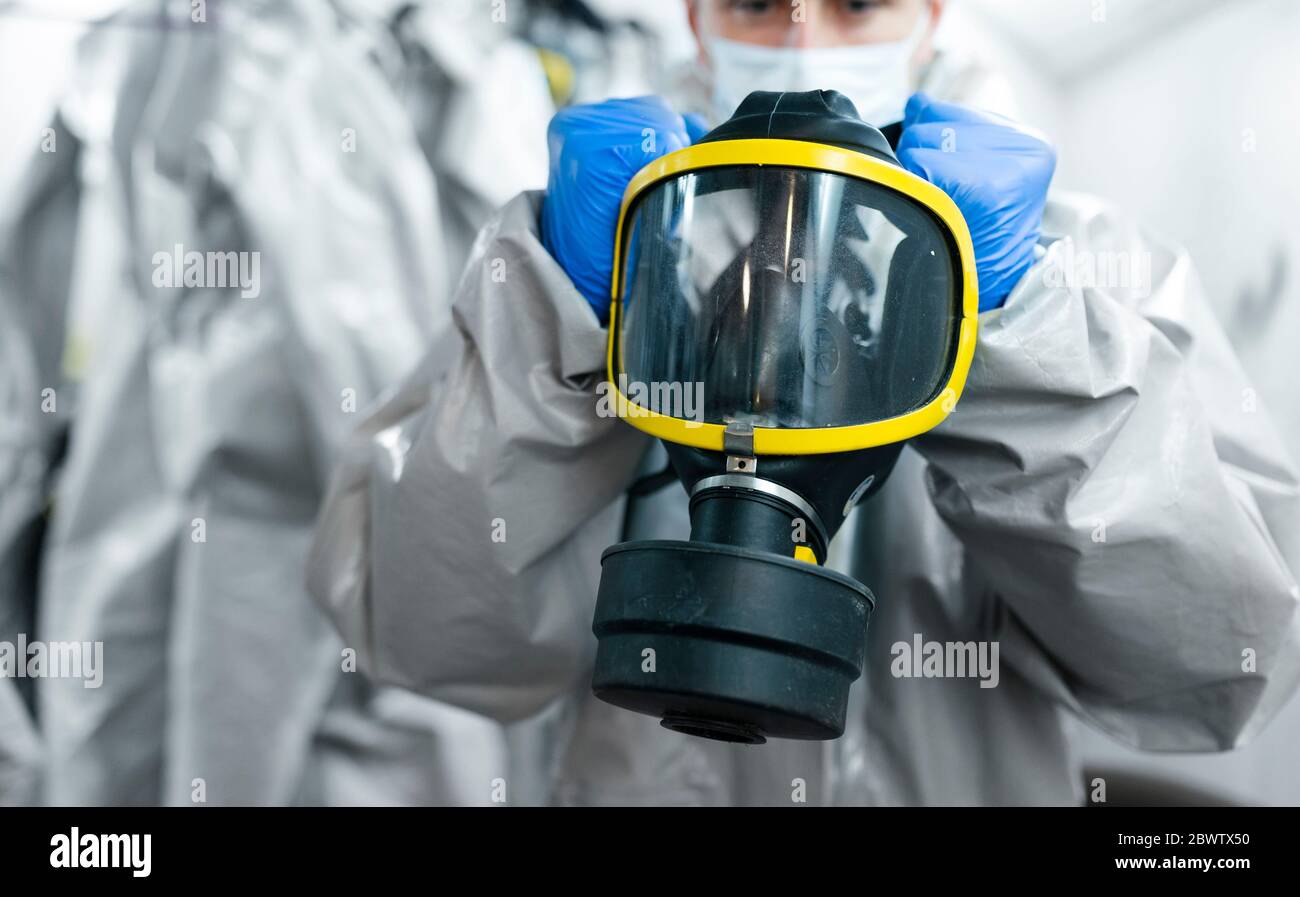 Close-up of sanitation worker holding gas mask while getting dressed in ...