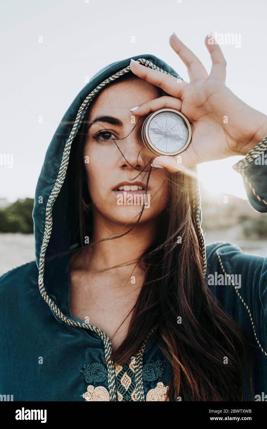 Portrait of young woman covering eye with compass, Morocco Stock Photo ...