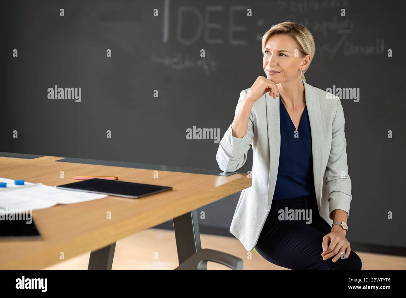 Confident blond businesswoman in conference room with blackboard Stock ...