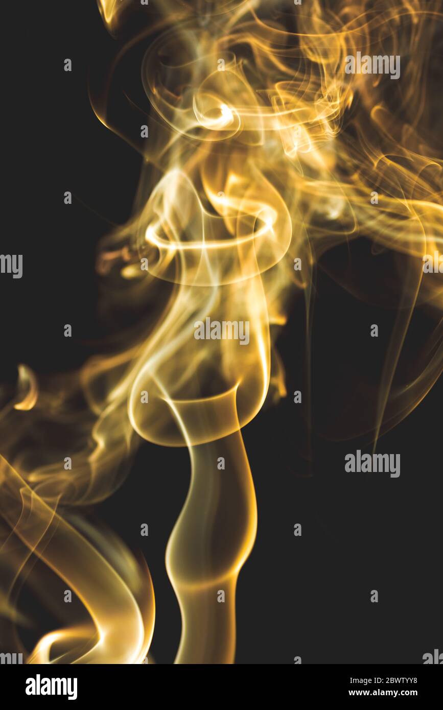 Yellow abstract shaped smoke against black background Stock Photo - Alamy