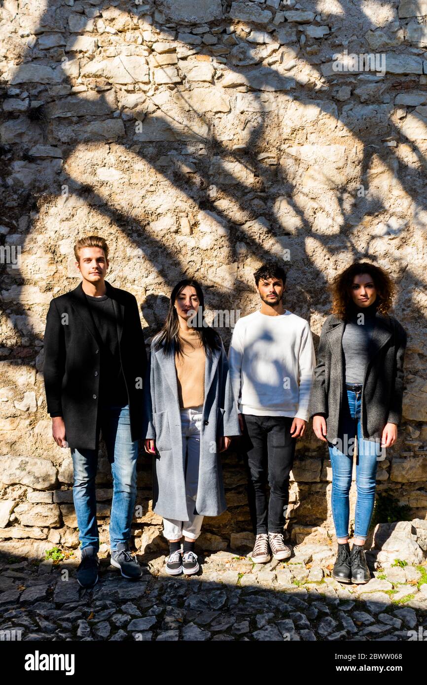 Portrait of four friends standing at a wall Stock Photo - Alamy