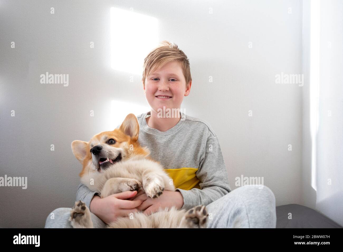 Portrait of boy sitting on bed at home cuddling his dog Stock Photo - Alamy