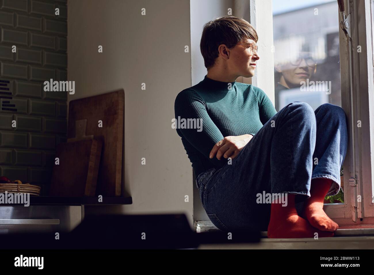 Pensive woman at home looking out of window Stock Photo - Alamy