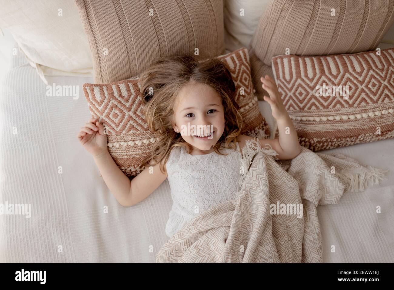 Portrait of happy little girl lying on bed Stock Photo - Alamy