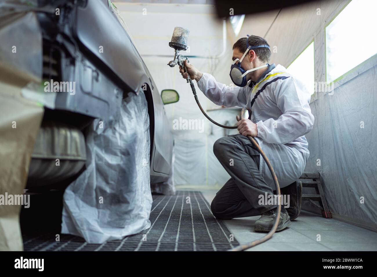 Body painter painting car in paint booth Stock Photo - Alamy