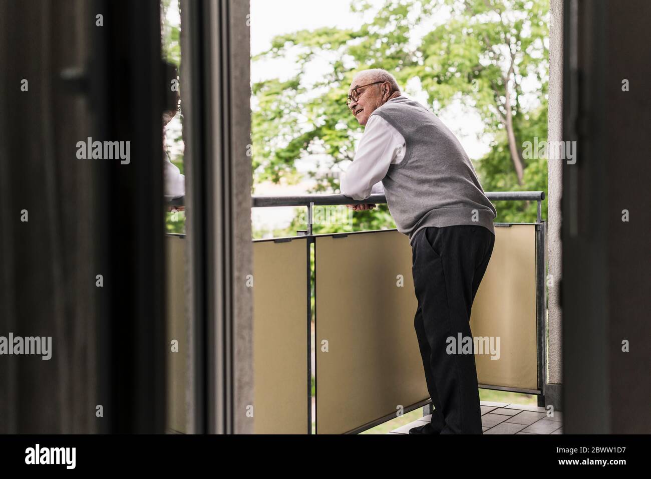Curious senior man standing on balcony watching something Stock Photo ...