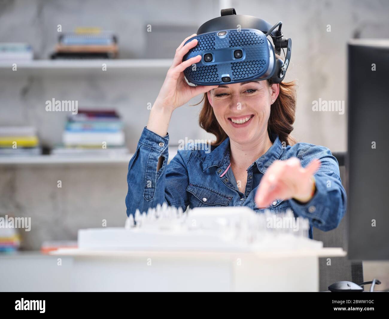 Smiling woman taking off VR glasses in modern office Stock Photo - Alamy