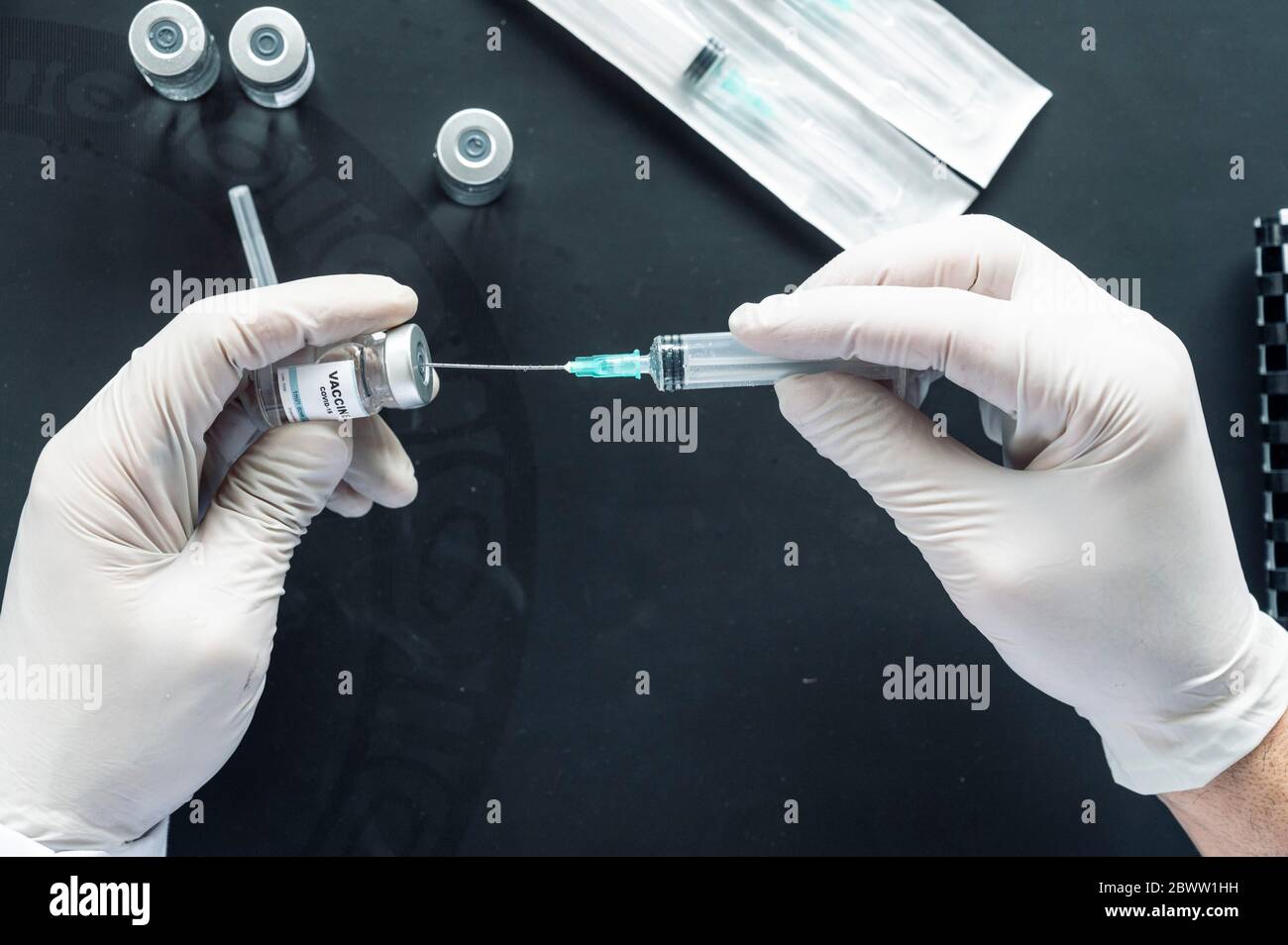 Cropped image of doctor's hand injecting syringe in vaccination vial ...