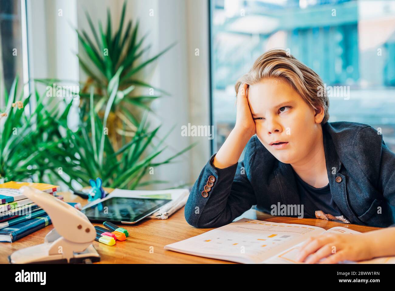 Frustrated boy sitting at desk with workbook Stock Photo - Alamy
