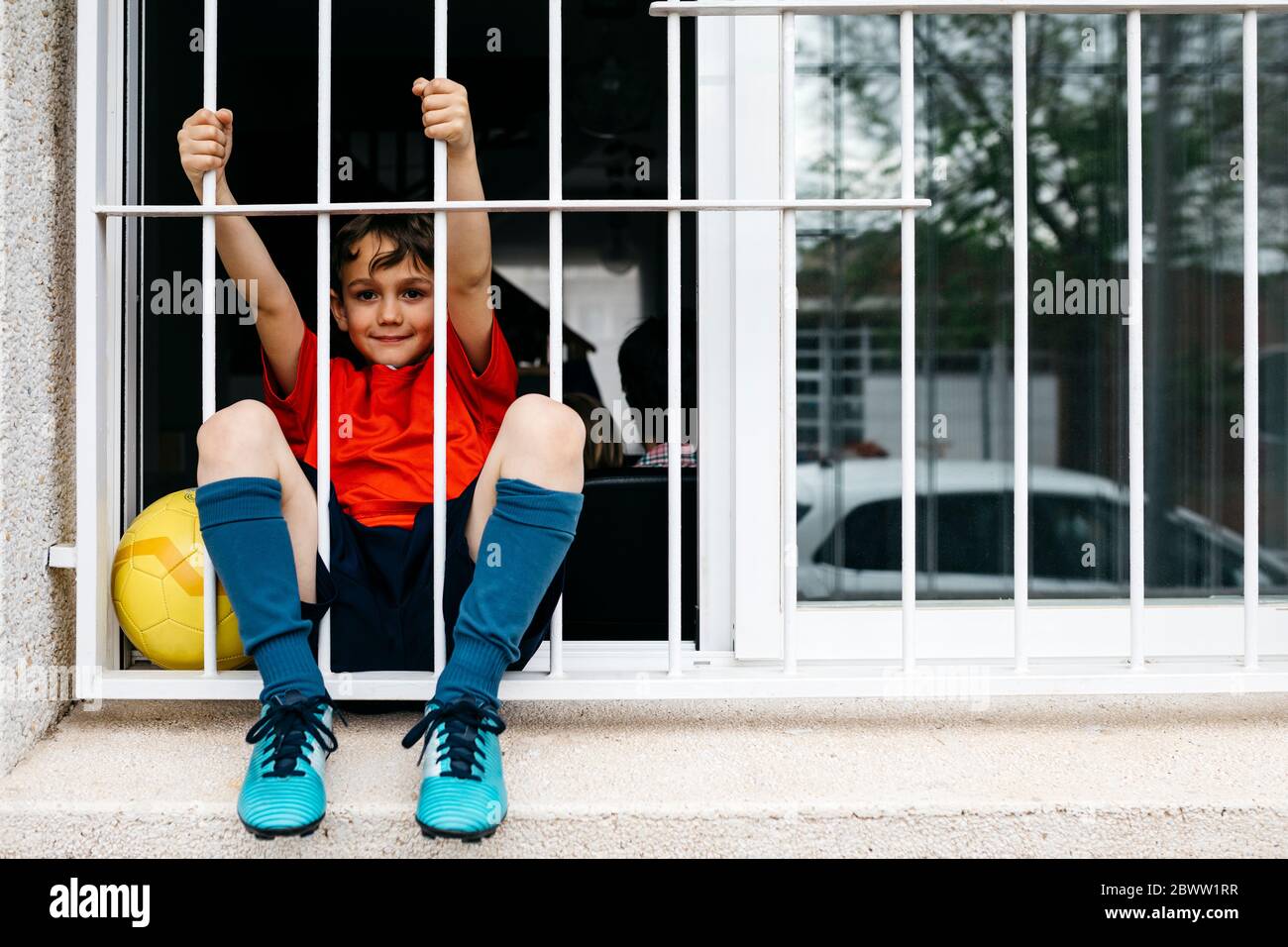 Boy with soccer ball at the window without being able to leave the ...