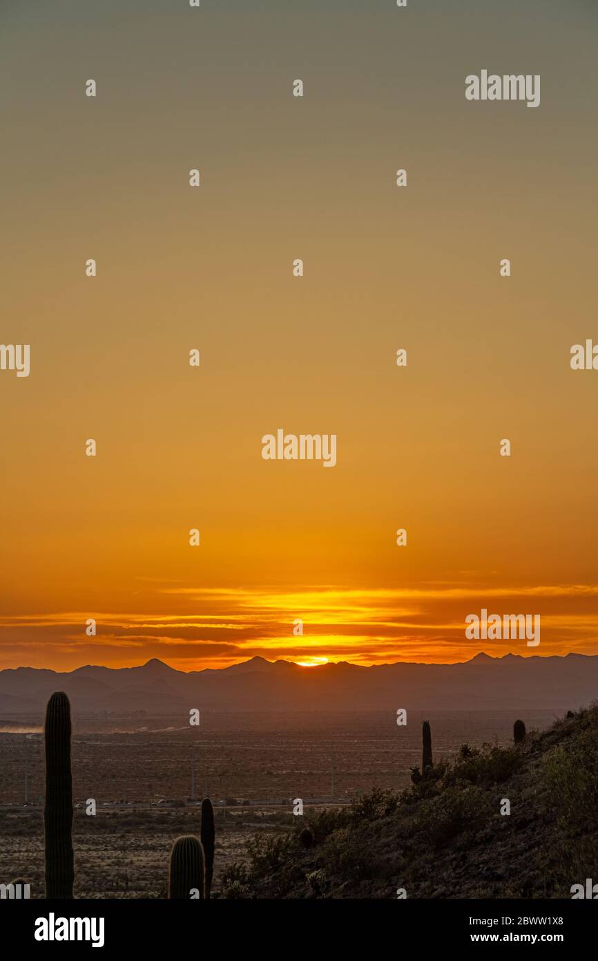 The sunsetting over distant mountains with an orange glow in the sky ...