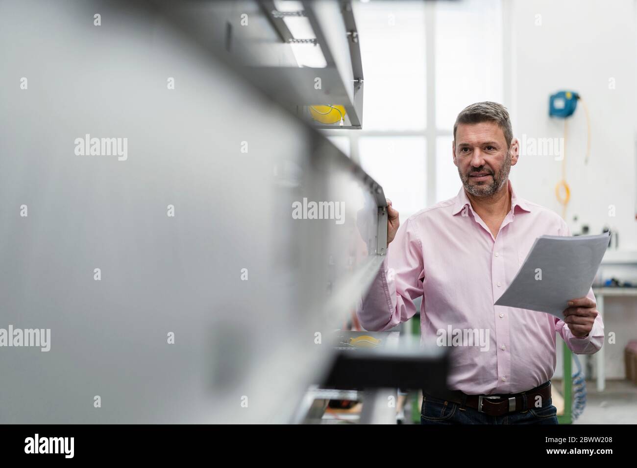 Mature man holding papers in a factory Stock Photo - Alamy