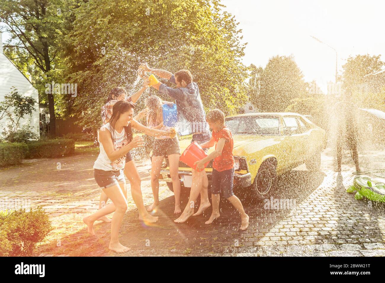Friends washing yellow vintage car in summer having fun Stock Photo - Alamy