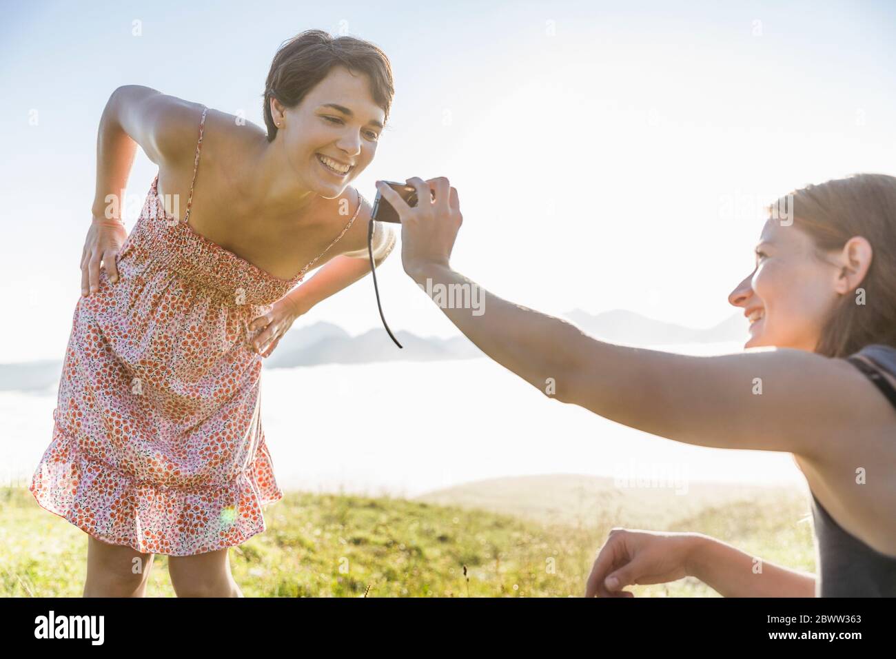Woman showing camera to her friend on meadow the mountains hi-res stock ...