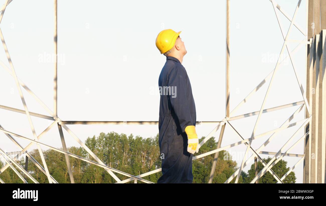 An electrician or builder and engineer, in a blue robe, in a yellow and ...