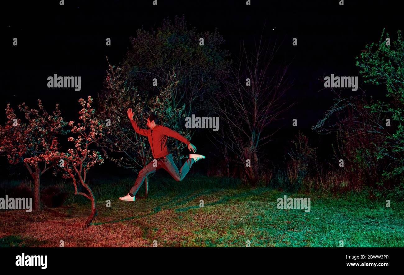 Man jumping in garden at night Stock Photo - Alamy