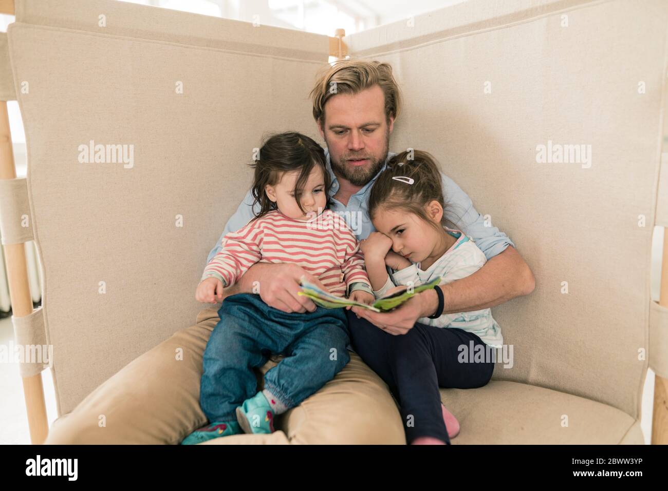 Father reading book to two daughters Stock Photo - Alamy