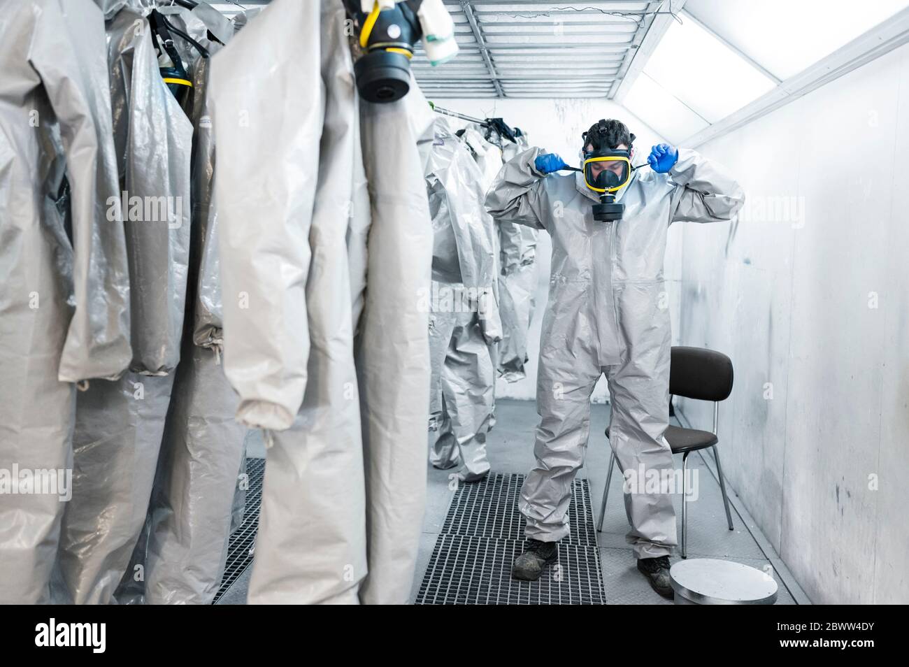 Full length of healthcare worker wearing gas mask while standing by ...