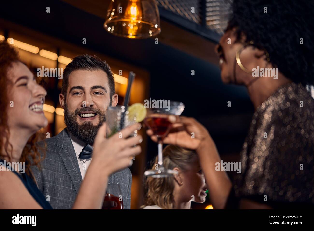 Happy friends socializing and drinking cocktails in a bar Stock Photo ...