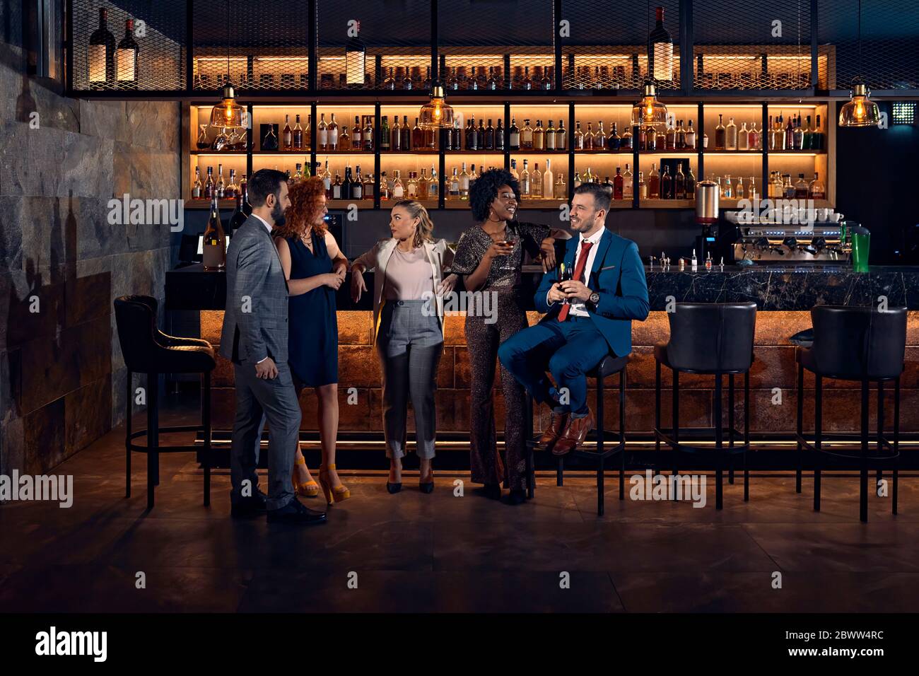 Friends socializing at the counter in a bar Stock Photo - Alamy