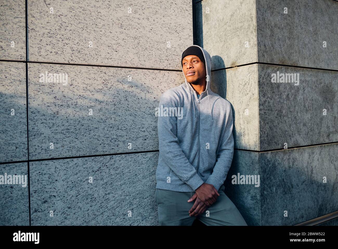 Portrait of young man leaning against a wall Stock Photo - Alamy