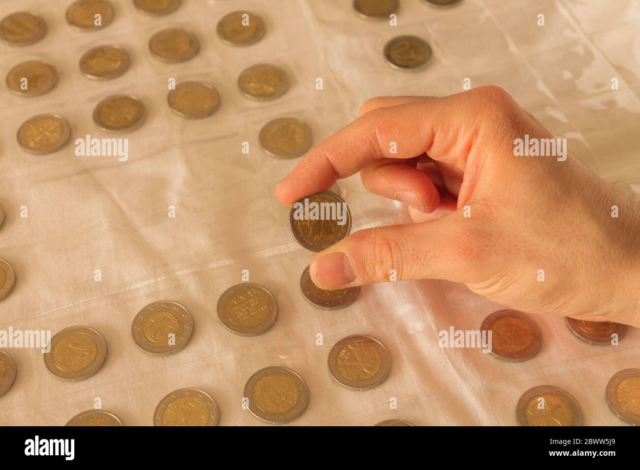Man hand holds 2 euro coin from a collection Stock Photo - Alamy