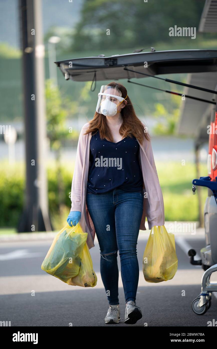 Customer walking with plastic bags at supermarket parking lot Stock ...