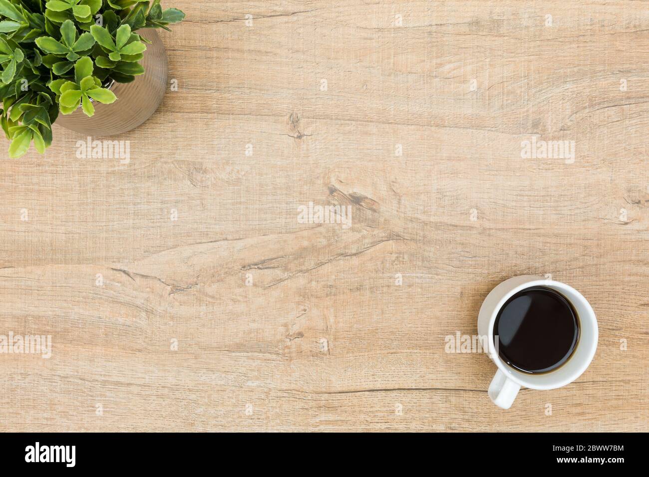 Minimal wood table with coffee and a small plant. Top view with copy ...