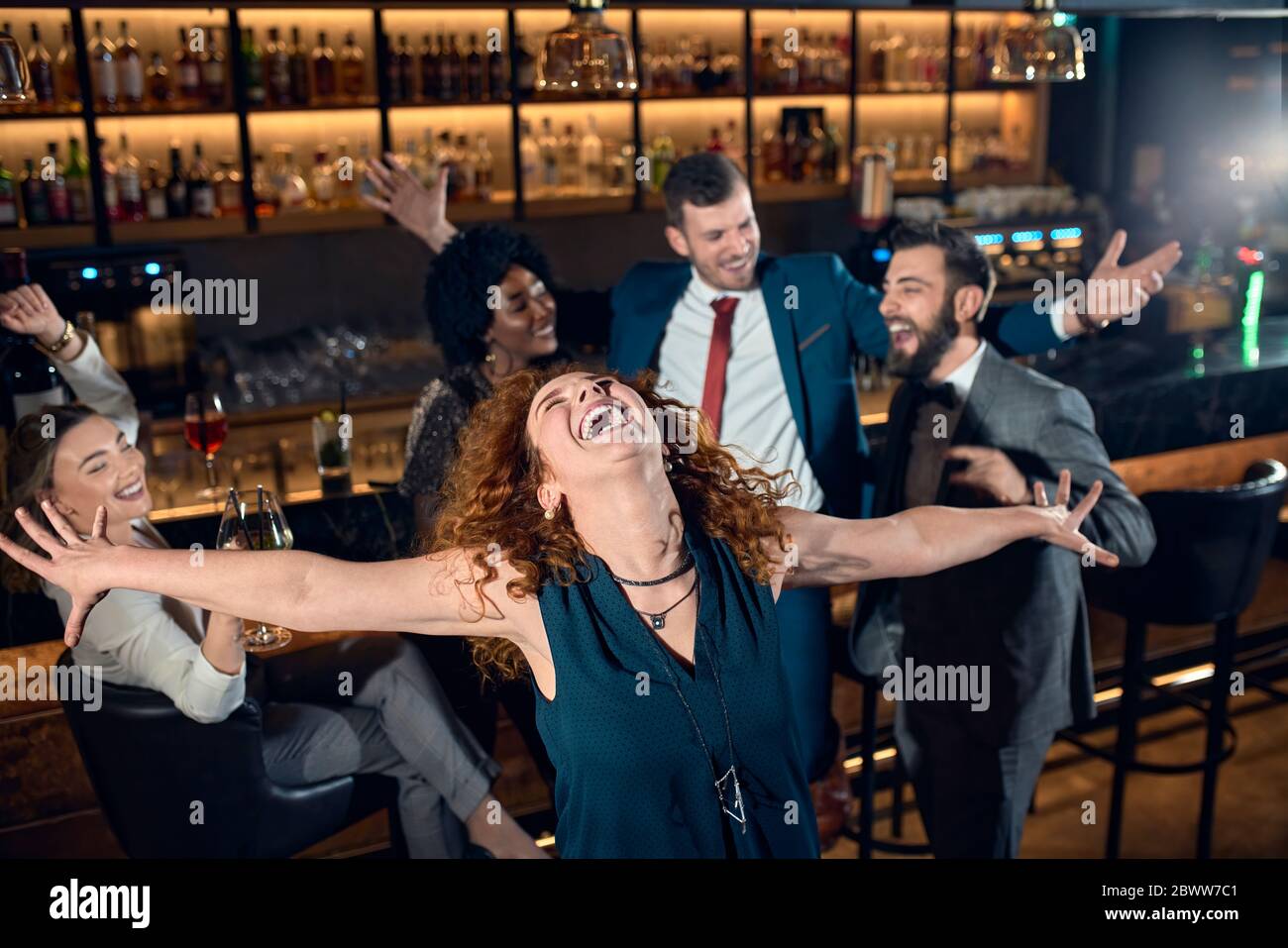 Exuberant young woman with friends dancing in a bar Stock Photo - Alamy
