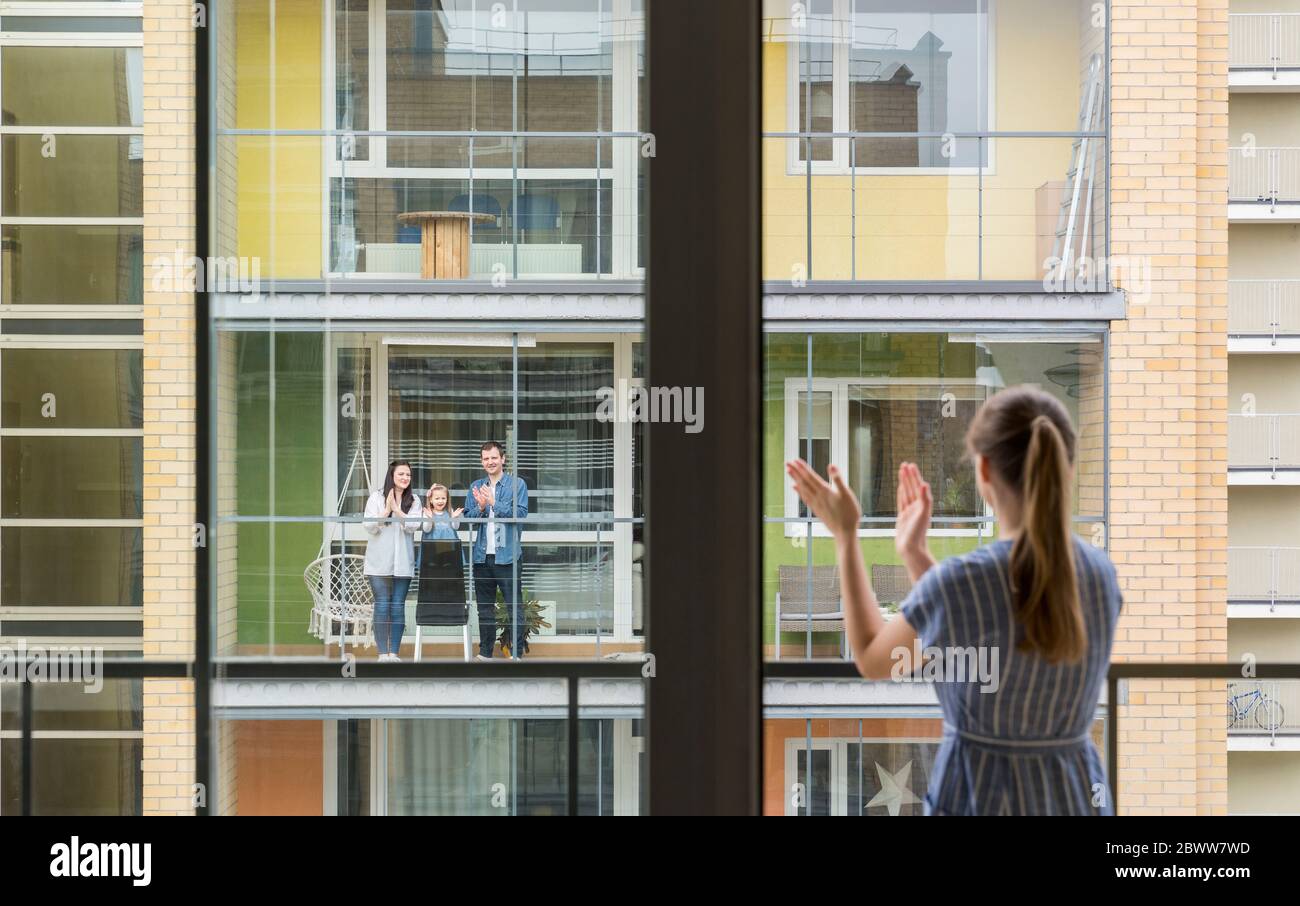 Back view of woman on balcony clapping hands and looking to her ...