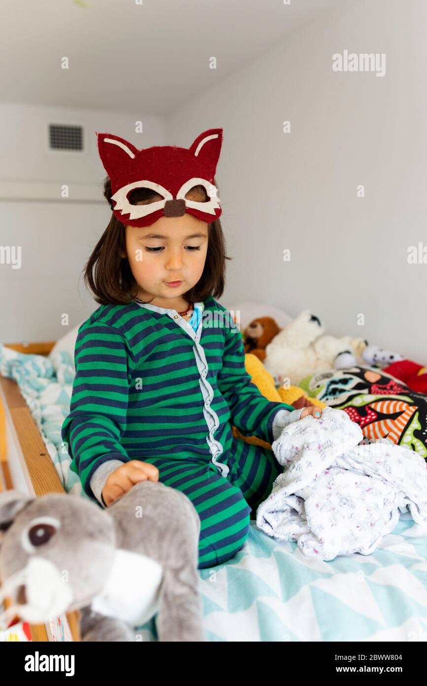 Portrait of little girl with fox mask crouching on bunk bed at home ...