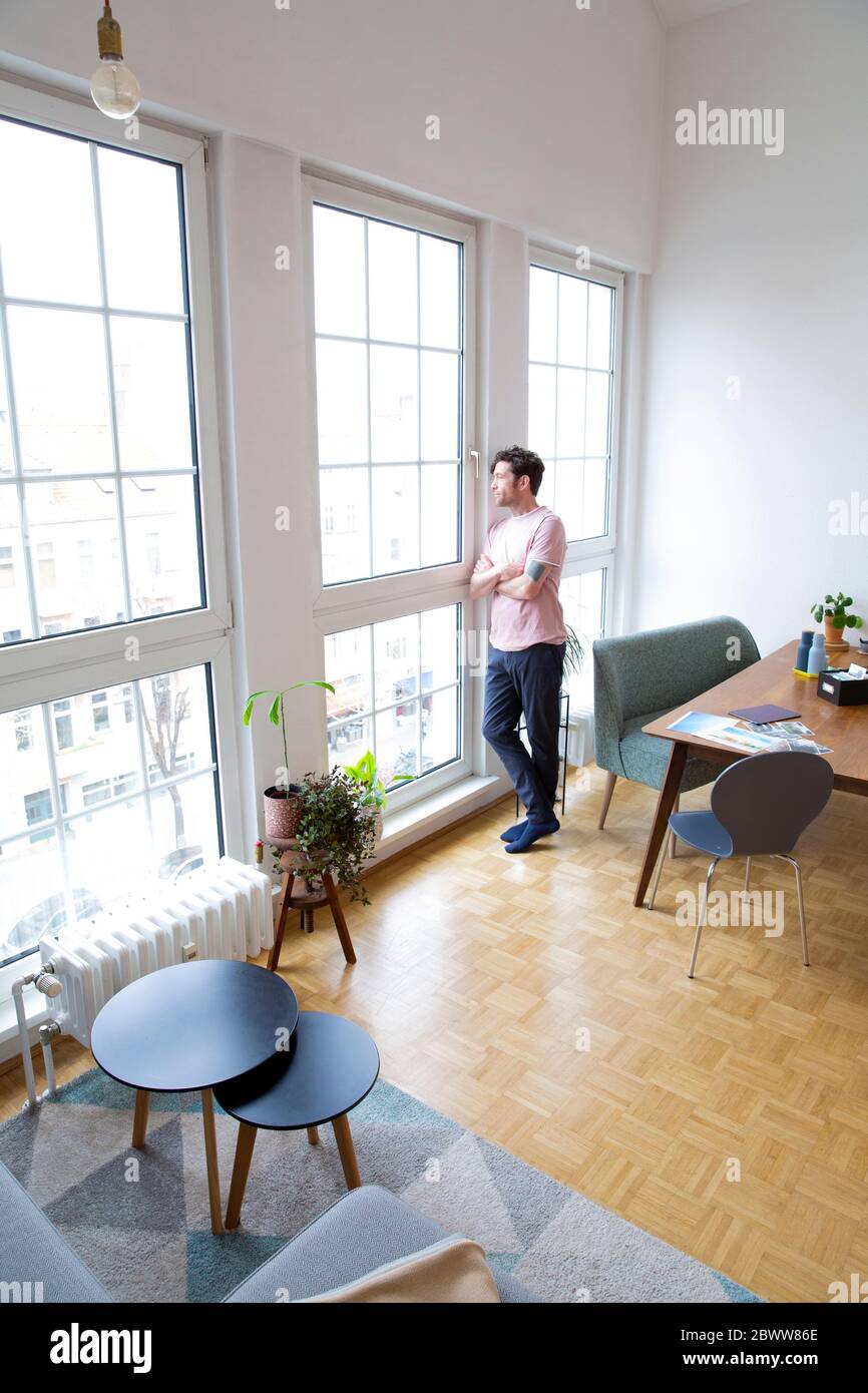 Man standing at the window at home looking out Stock Photo - Alamy
