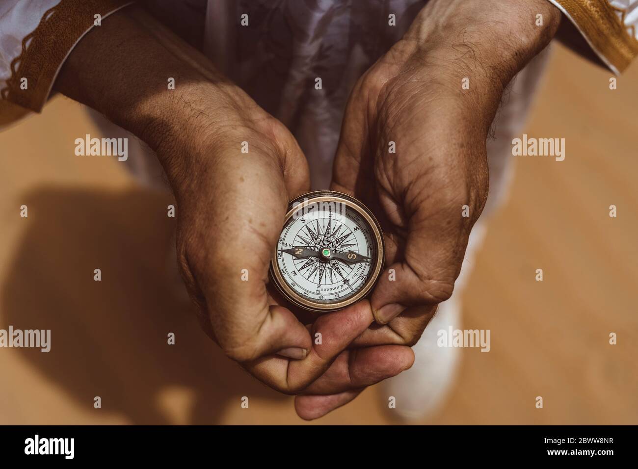 Hands holding compass in the desert, elevated view Stock Photo - Alamy