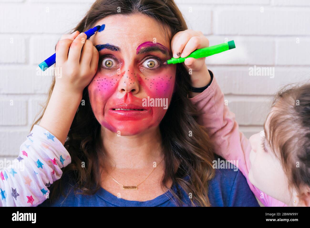 Daughters painting coloful make up on mother's face Stock Photo - Alamy