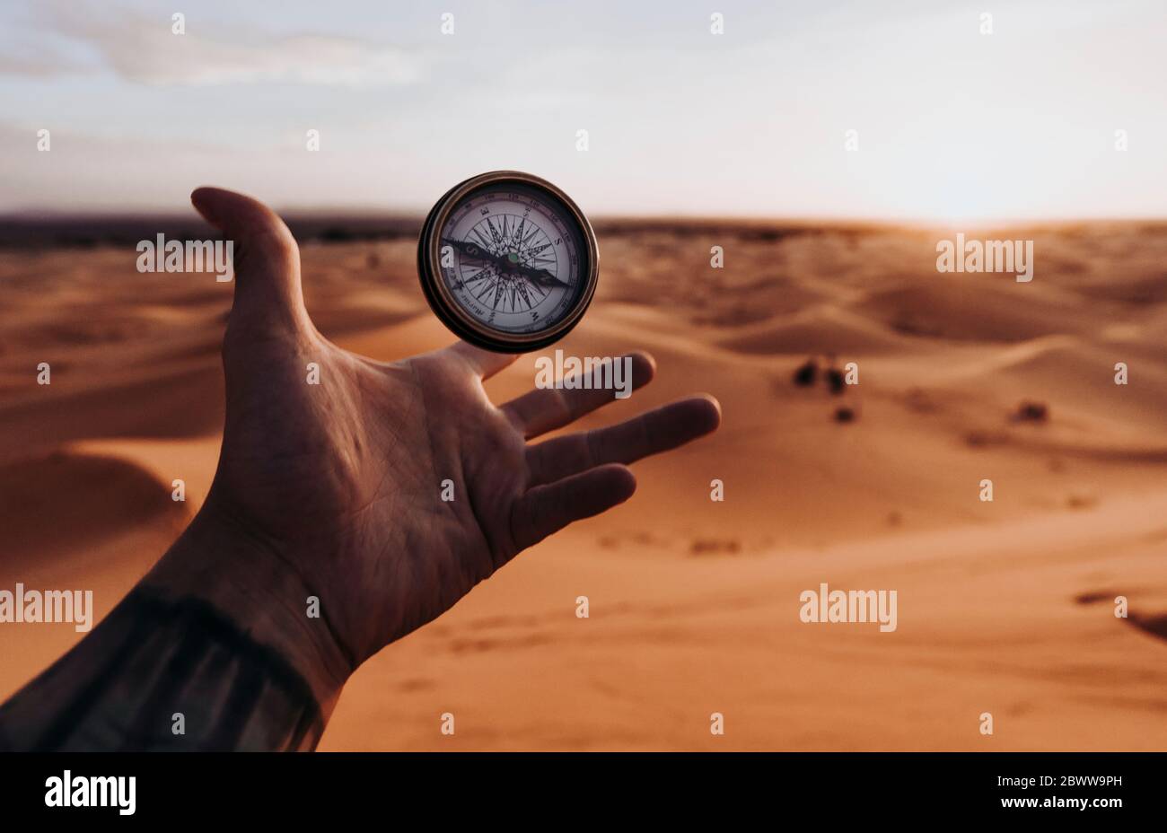 Hand catching compass in the desert Stock Photo - Alamy