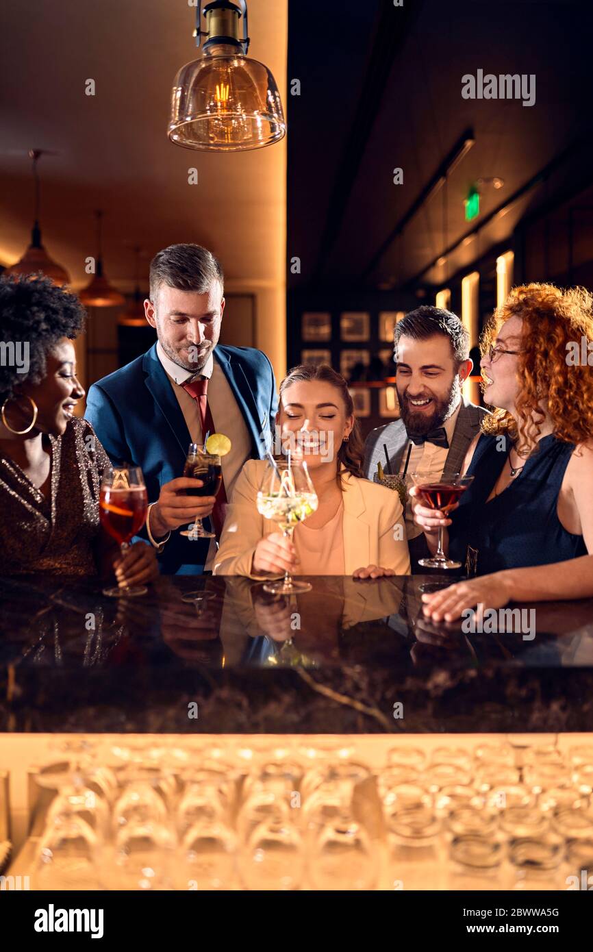 Happy friends socializing in a bar with cocktails Stock Photo - Alamy