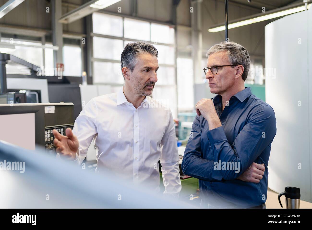 Businessmen in factory having a meeting in production hall Stock Photo ...