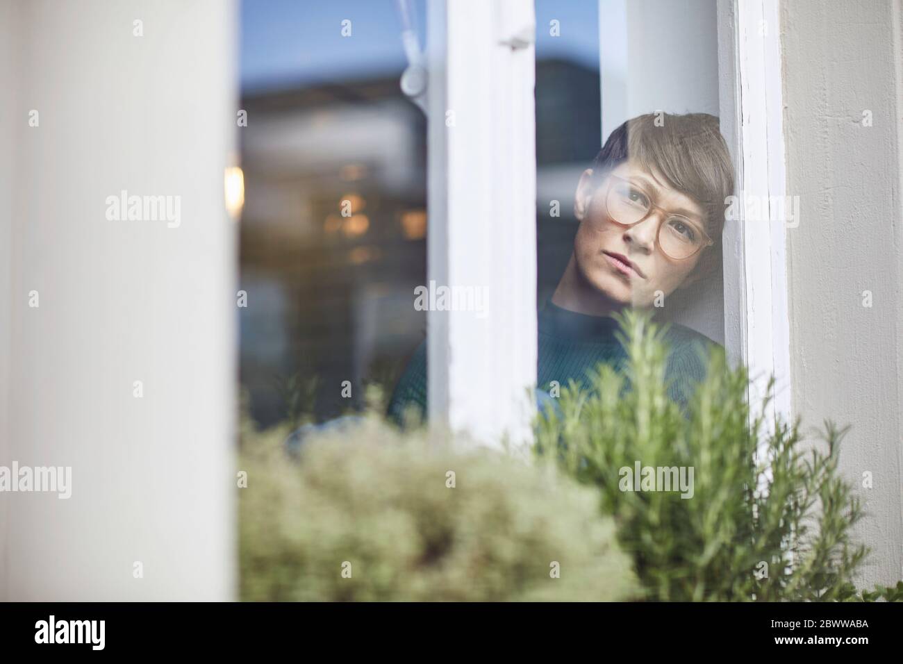 Pensive woman at home looking out of window Stock Photo - Alamy
