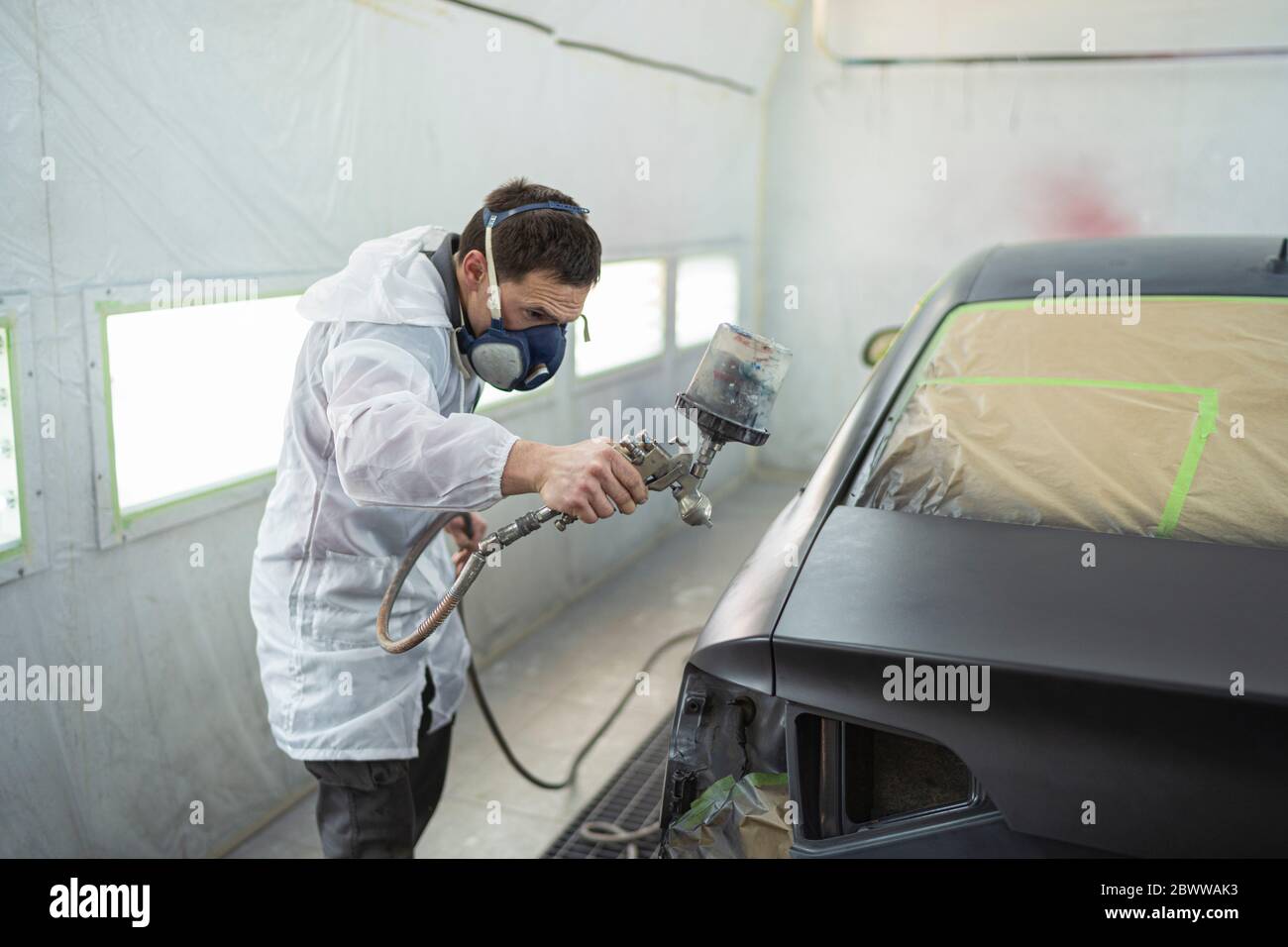 Body painter painting car in paint booth Stock Photo - Alamy