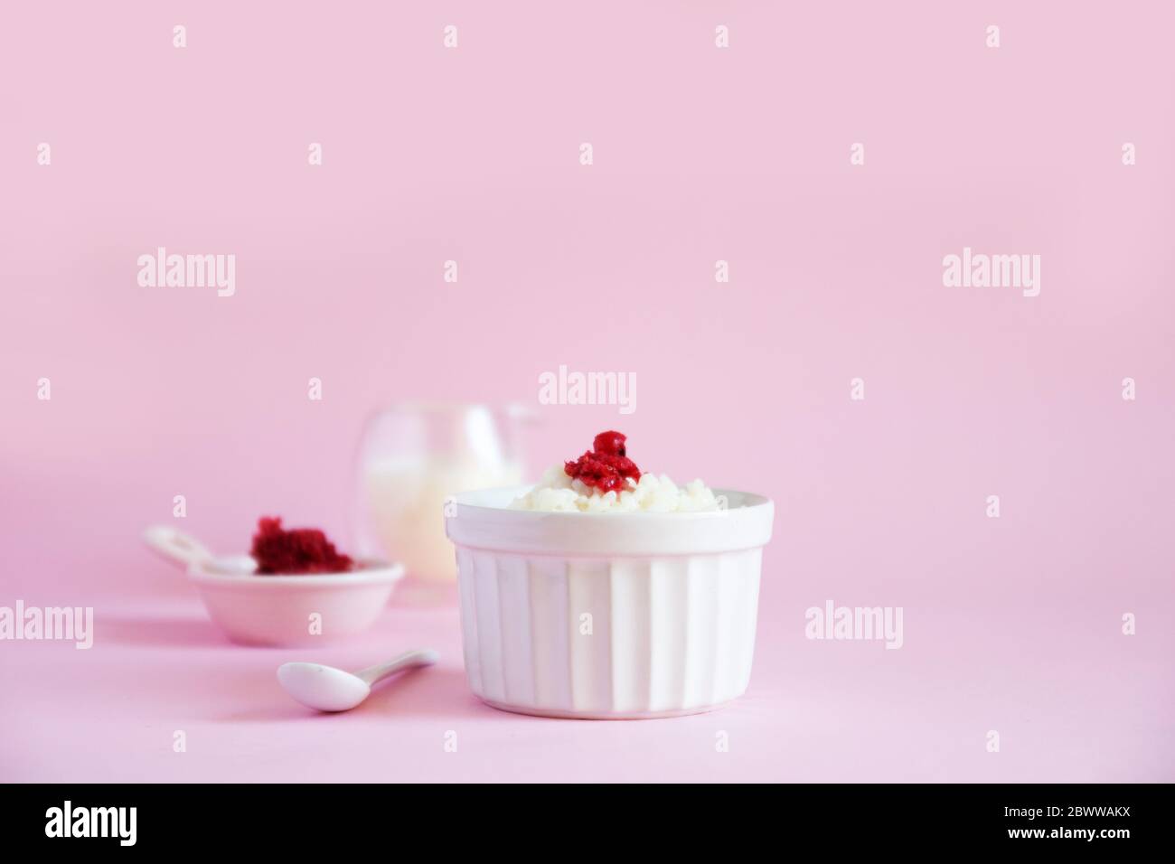 Milk rice porridge with frozen berries on a pink background Stock Photo ...