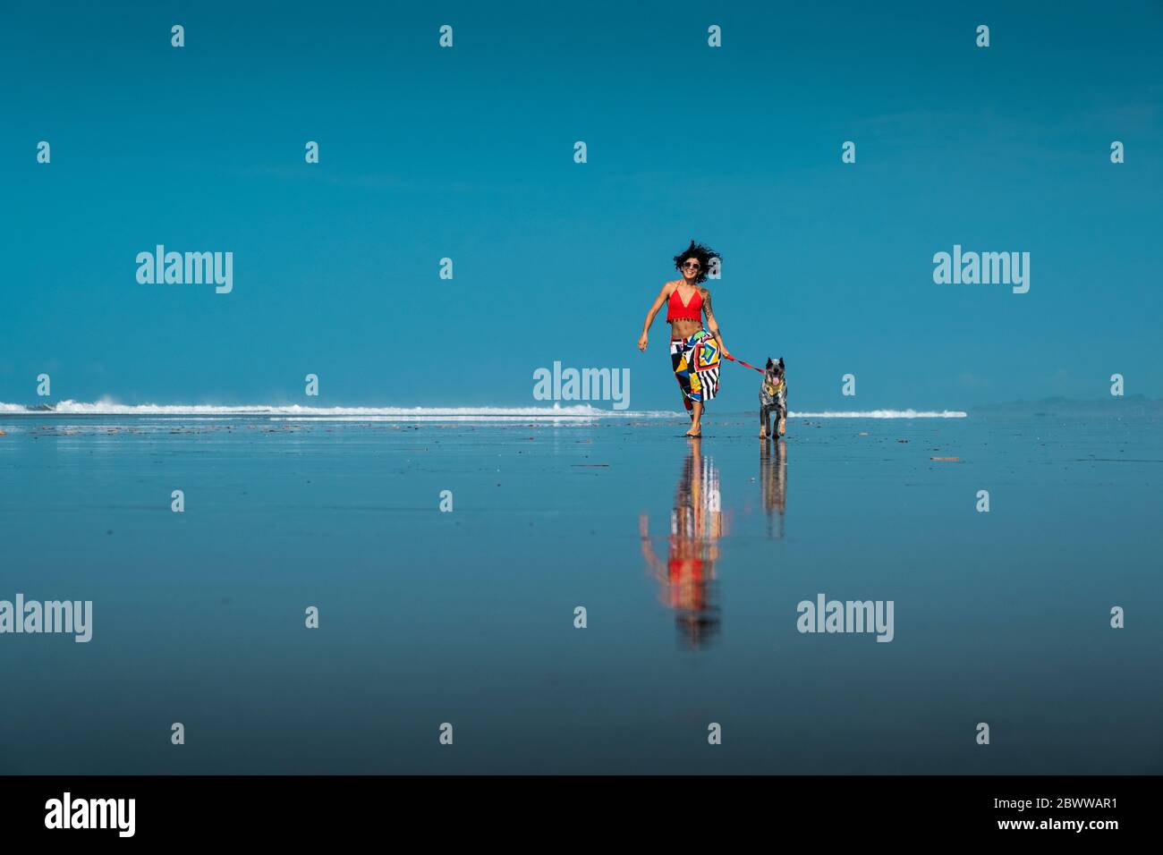 Carefree young woman taking her dog for a walk at the beach, Costa Rica ...