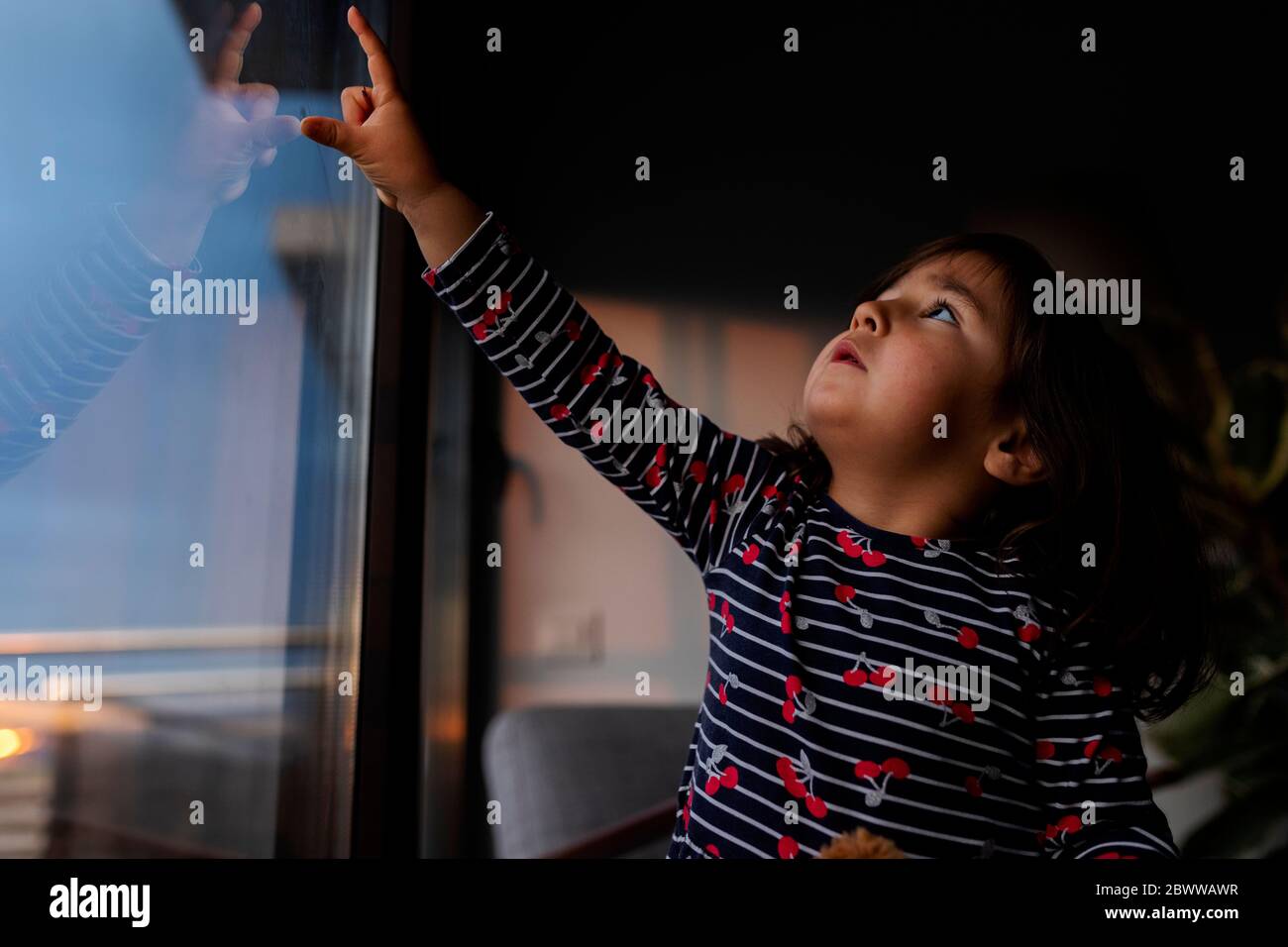 Little girl looking out of window in the evening Stock Photo - Alamy