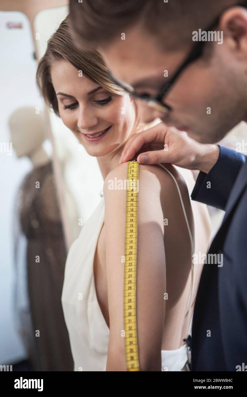 Fashion designer taking measurements of woman Stock Photo - Alamy