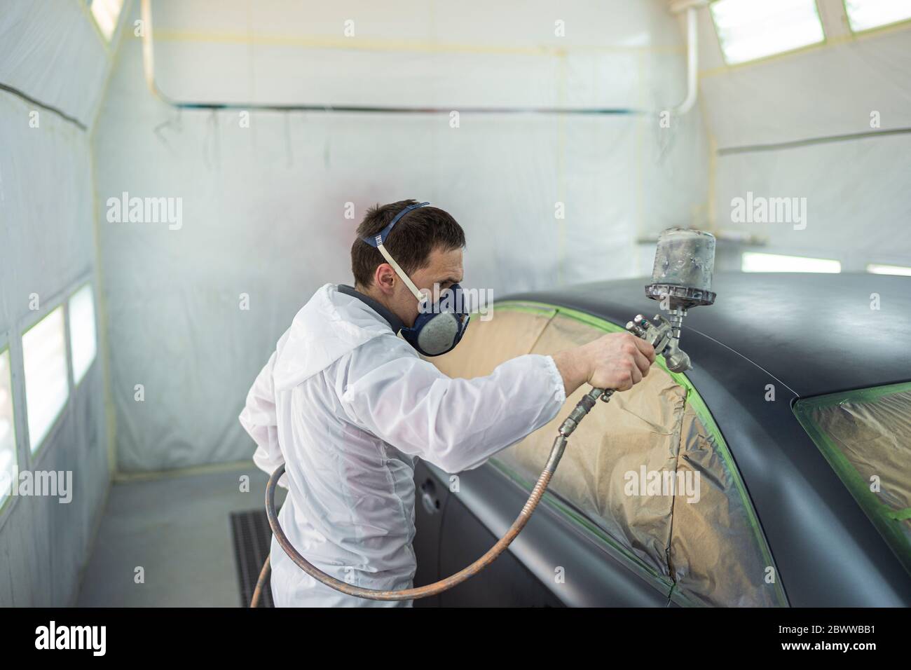 Body painter painting car in paint booth Stock Photo - Alamy
