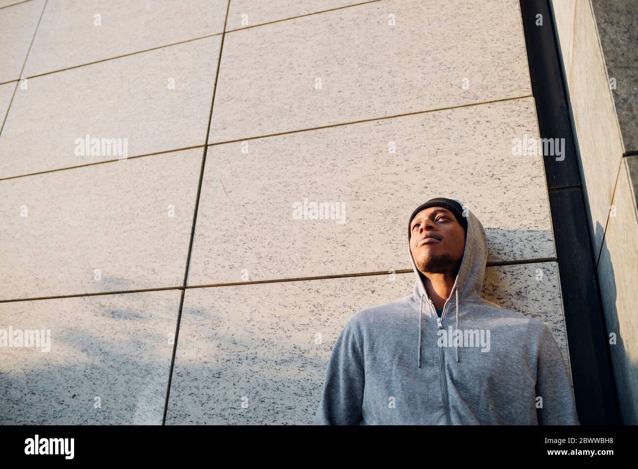 Portrait of young man leaning against a wall Stock Photo - Alamy