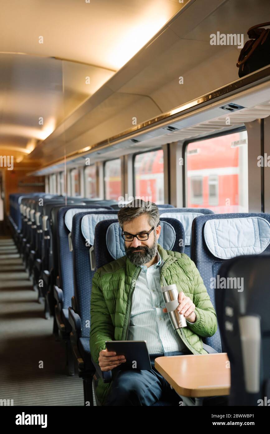 Man sitting in train using tablet Stock Photo - Alamy