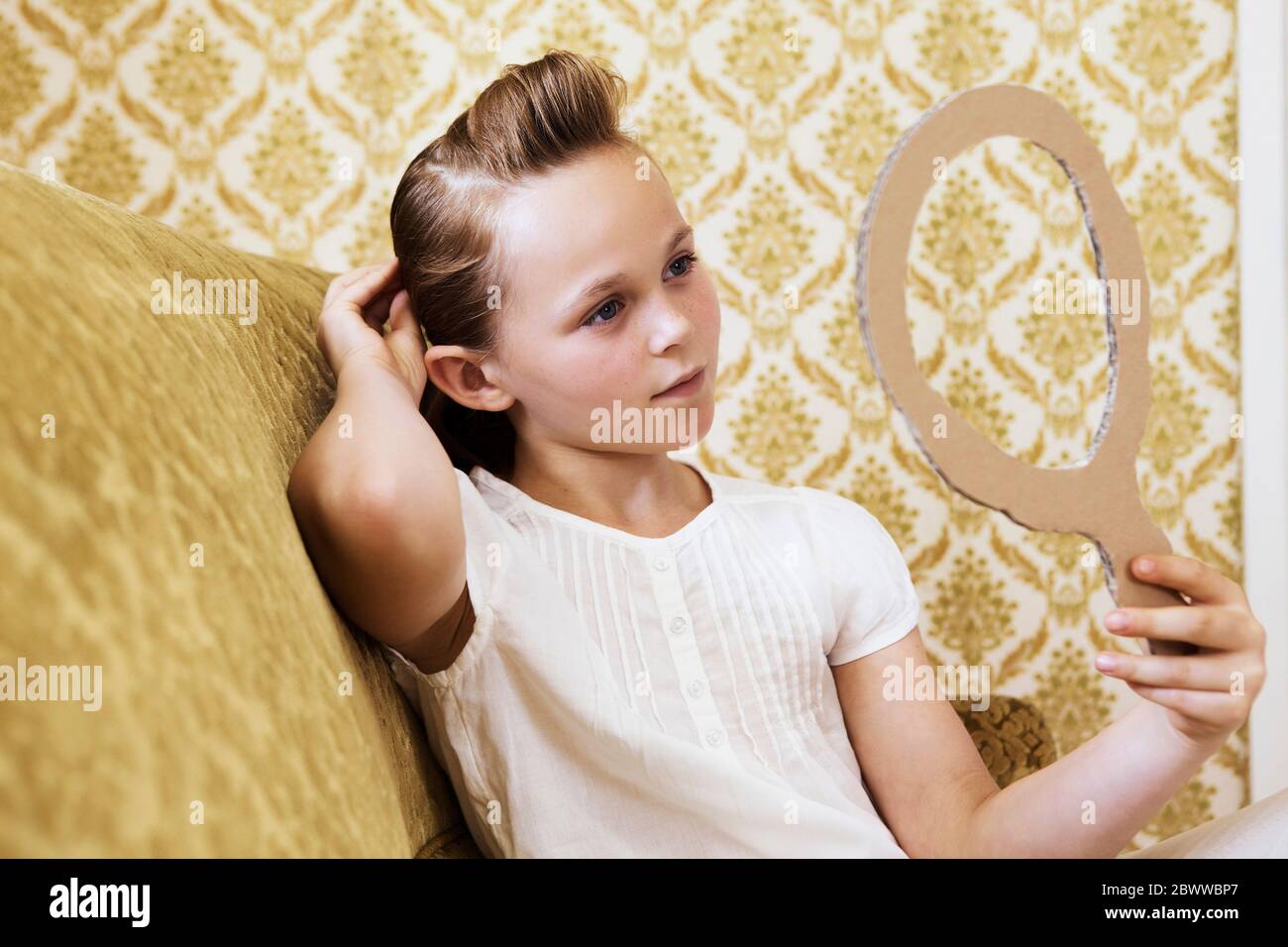 Portrait of girl on a couch looking in cardboard mirror Stock Photo - Alamy