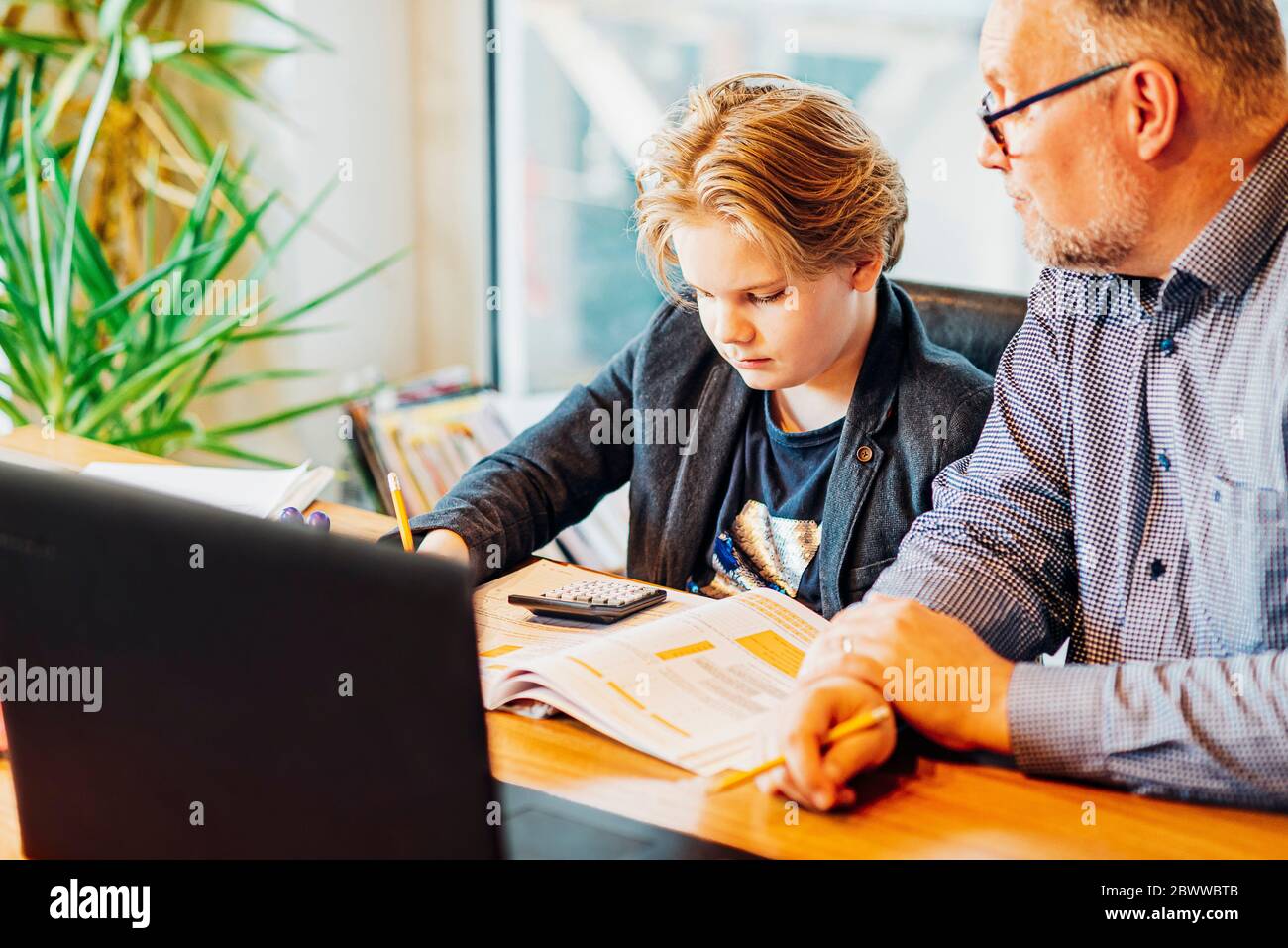 Father helping son doing homework at desk Stock Photo - Alamy