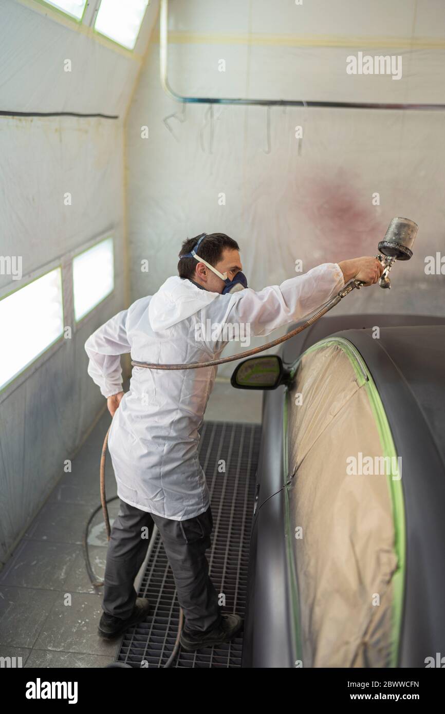 Body painter painting car in paint booth Stock Photo - Alamy